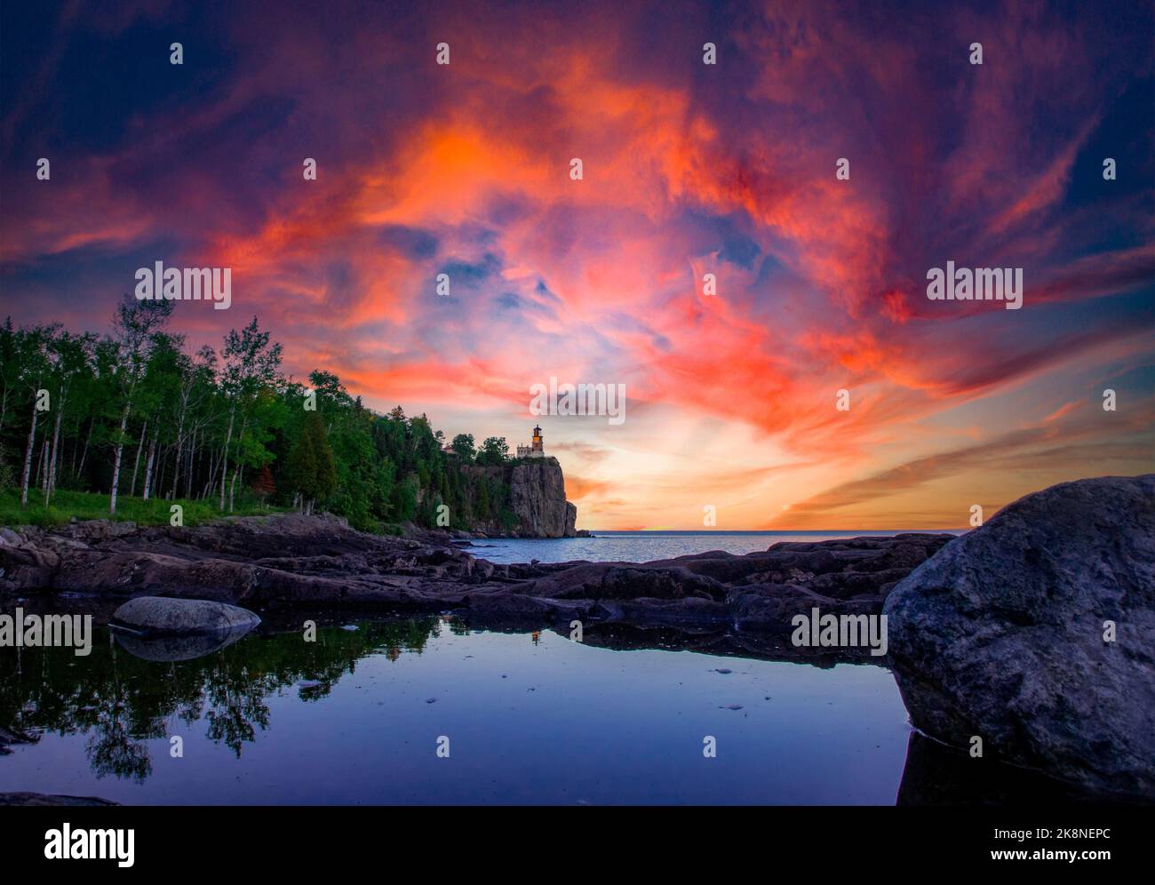 The Split Rock lighthouse on the cliff under the orange and blue sunset ...