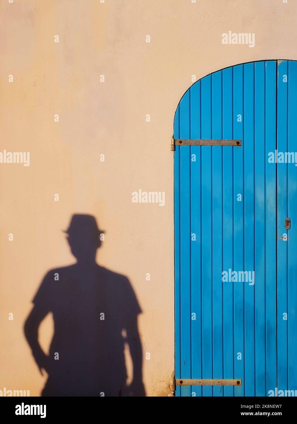 The shadow of a man reflected on a wall of a house with a blue wooden ...