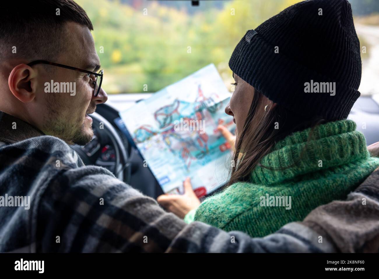 A man and lady holding and looking at paper map, sitting inside car ...