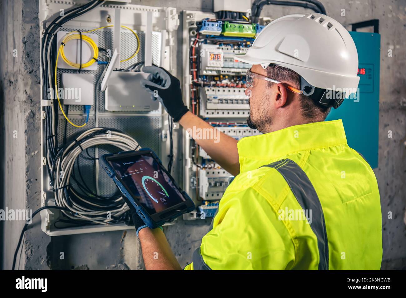 Man, an electrical technician working in a switchboard with fuses, uses a tablet Stock Photo - Alamy