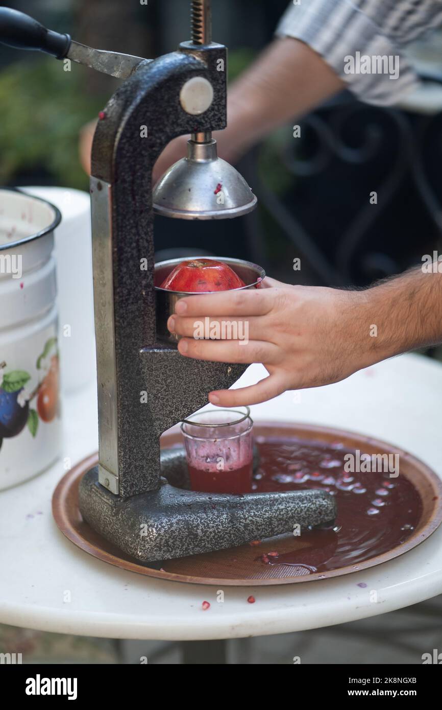 Process of squeezing pomegranate juice using manual mechanical juicer ...