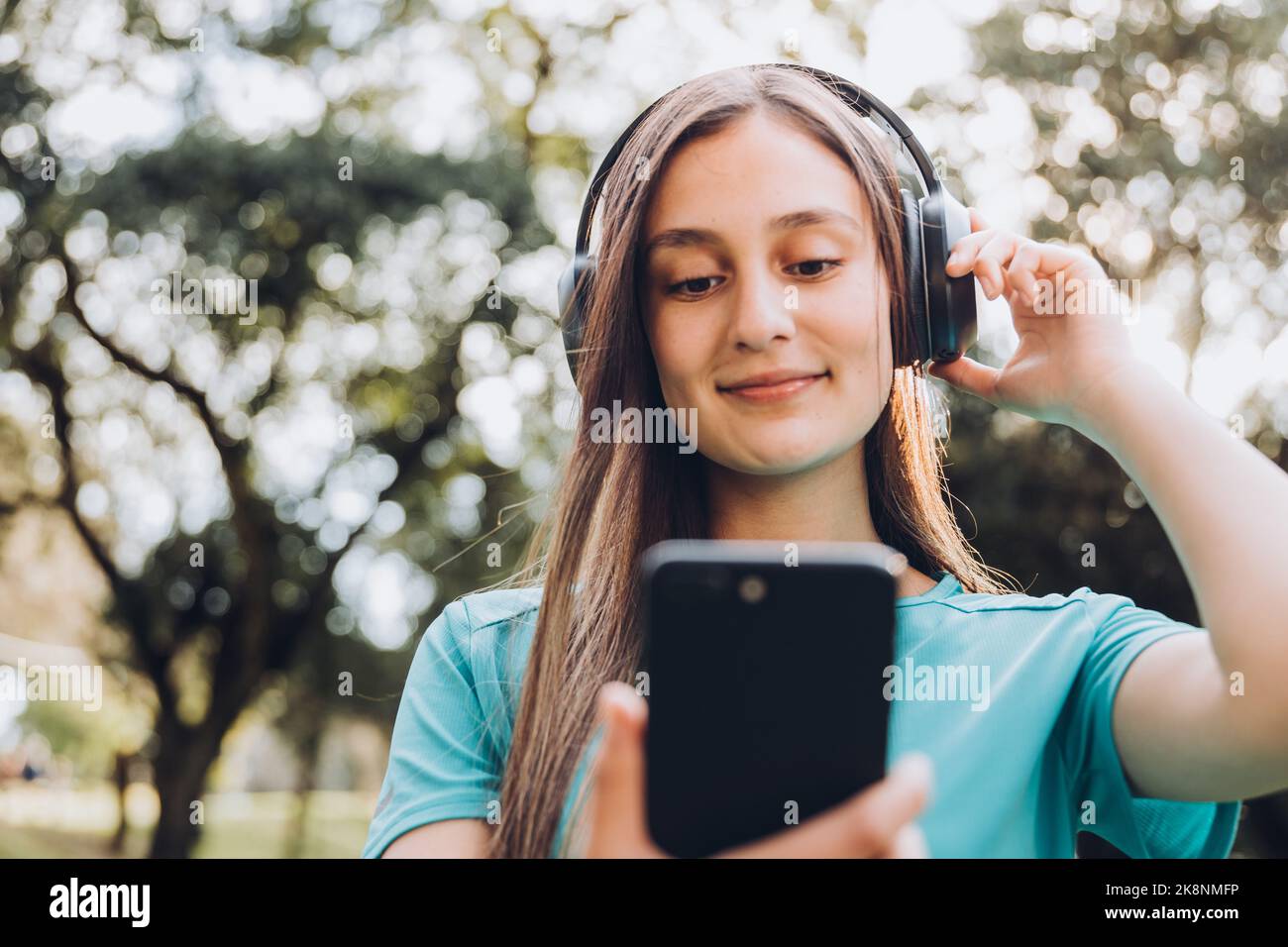 Teenage girl using headphones and listening to music on her smartphone ...