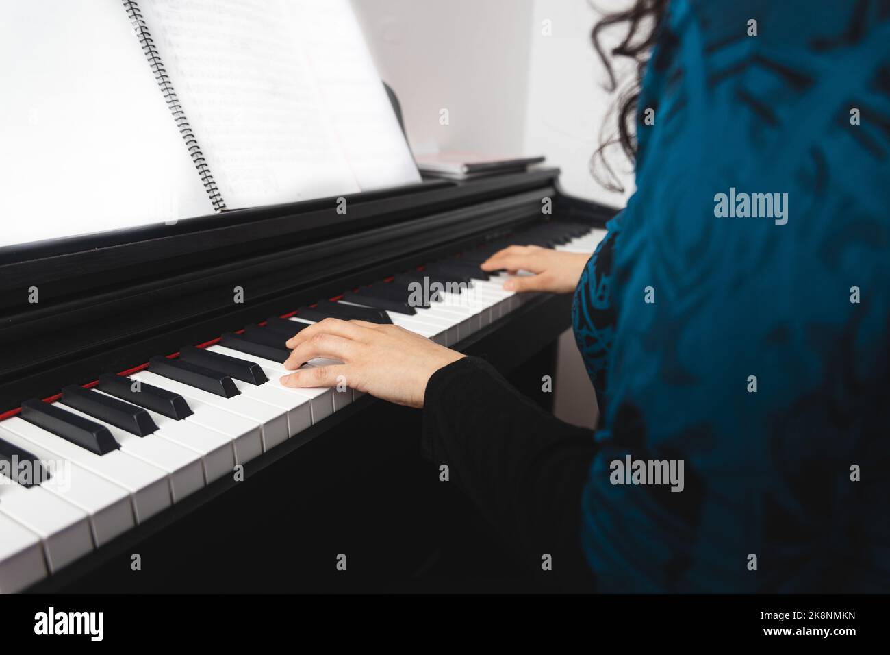 Close up of woman's hands playing piano by reading sheet music ...