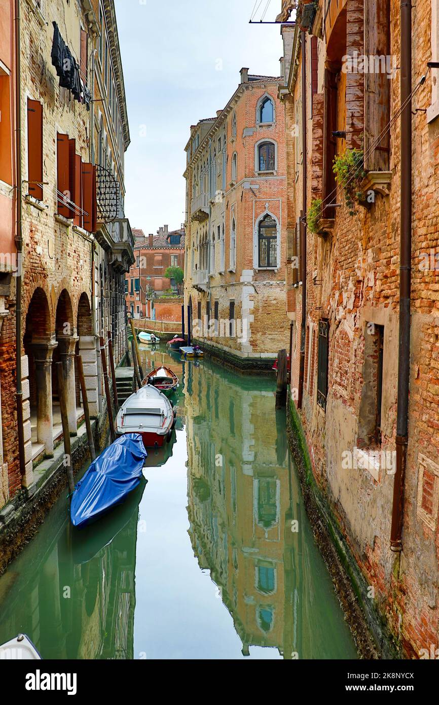 A vertical shot of a canal in Venice with gondolas floating on the ...