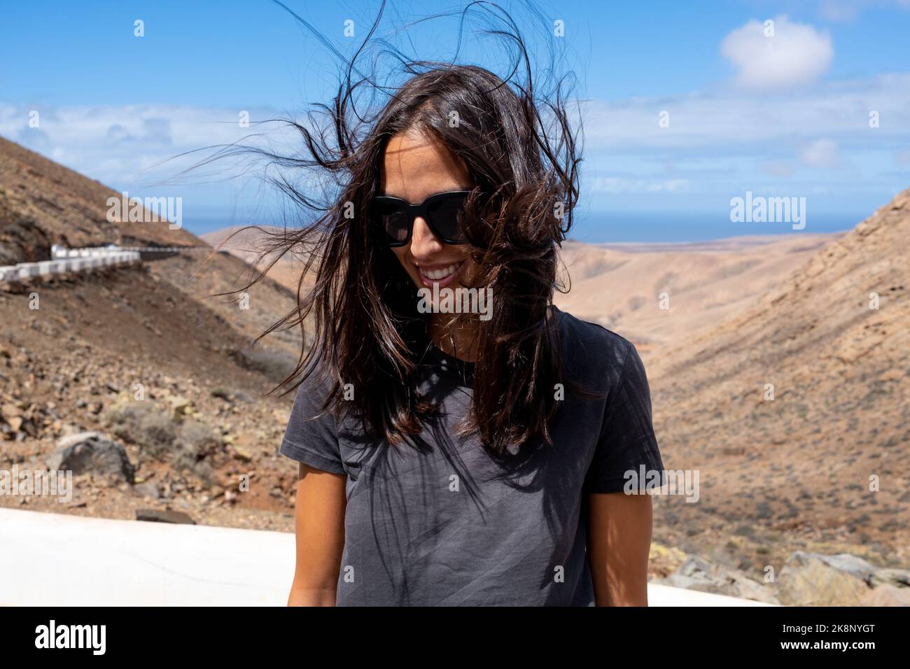 Portrait of young smiling woman face partially covered with flying hair ...