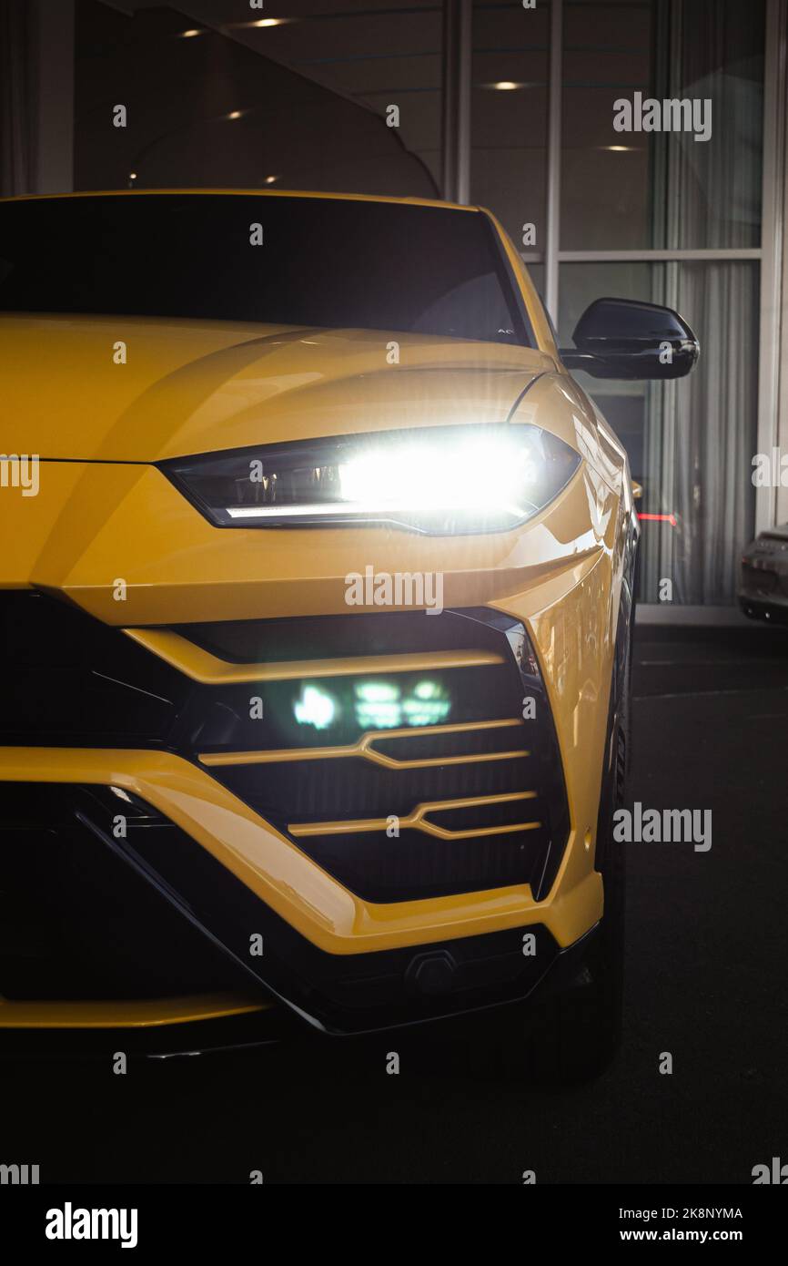 a vertical of Yellow Lamborghini Urus front view with headlights on ...