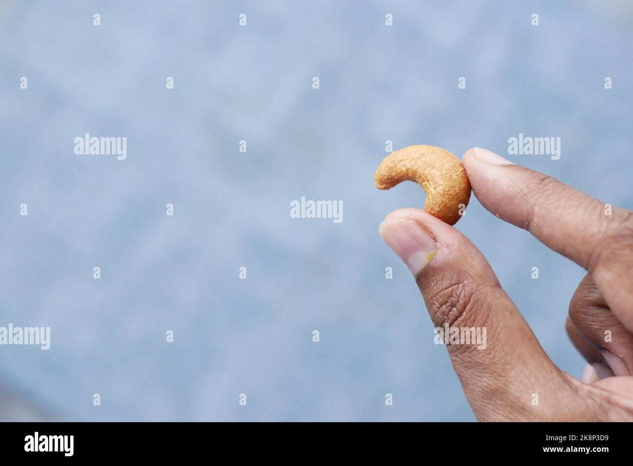holding a cashew nut on gray background Stock Photo - Alamy