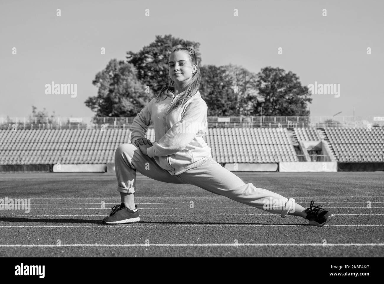 Athletic girl child do outward lunging during sports lesson at ...