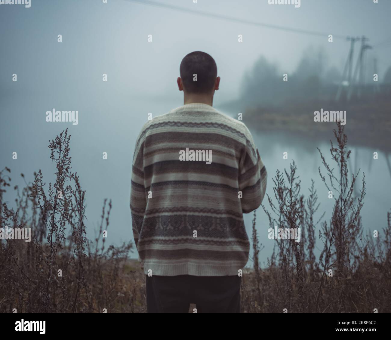 lonely man standing and looking at river foggy day. depressive ...