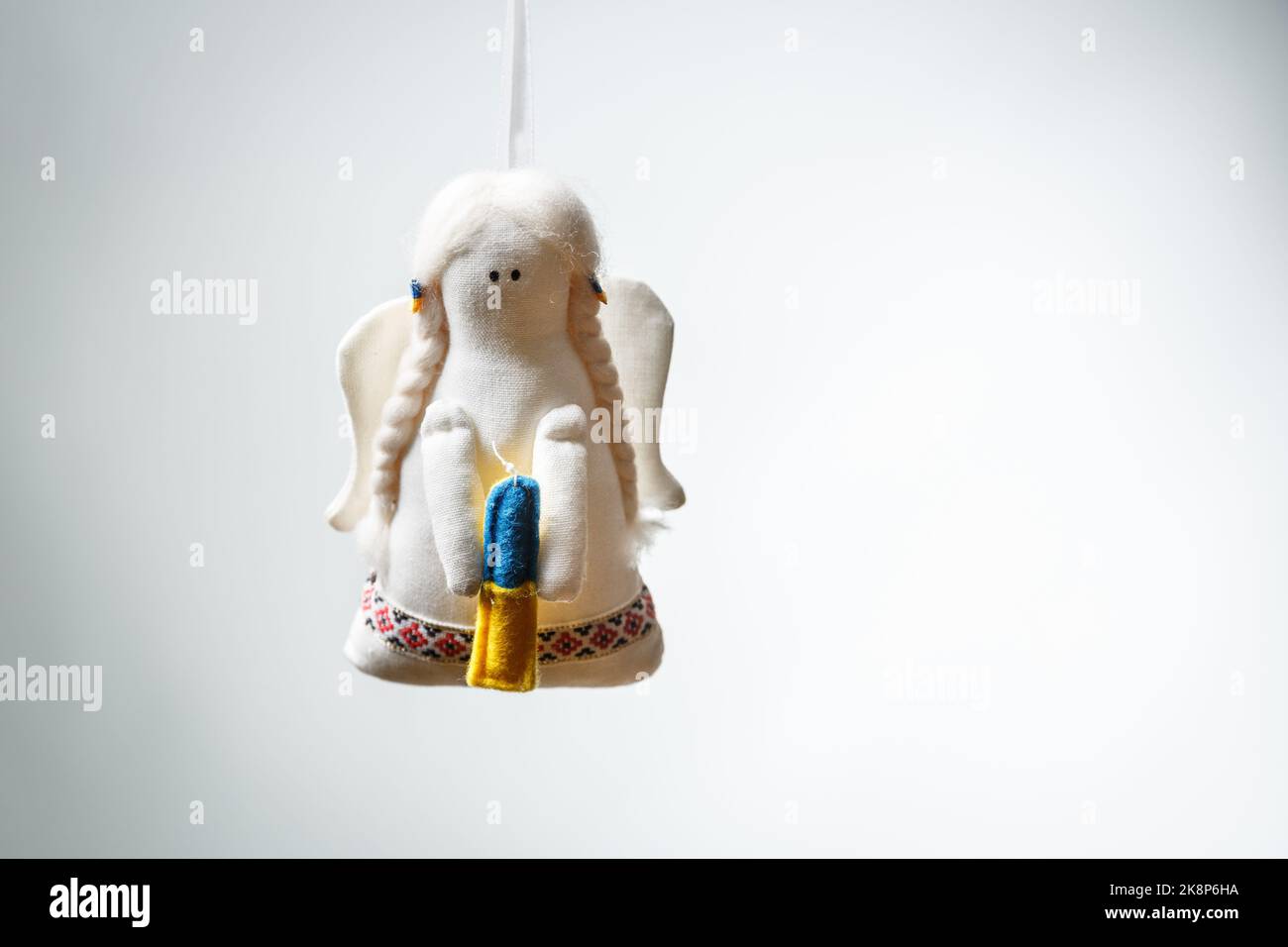 White fabric soft angel toy with wings holding a candle with a color of ...