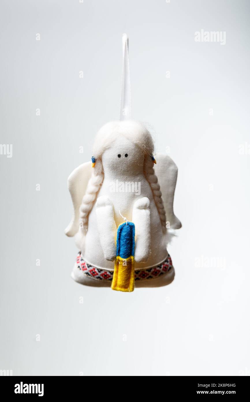 White fabric soft angel toy with wings holding a candle with a color of ...