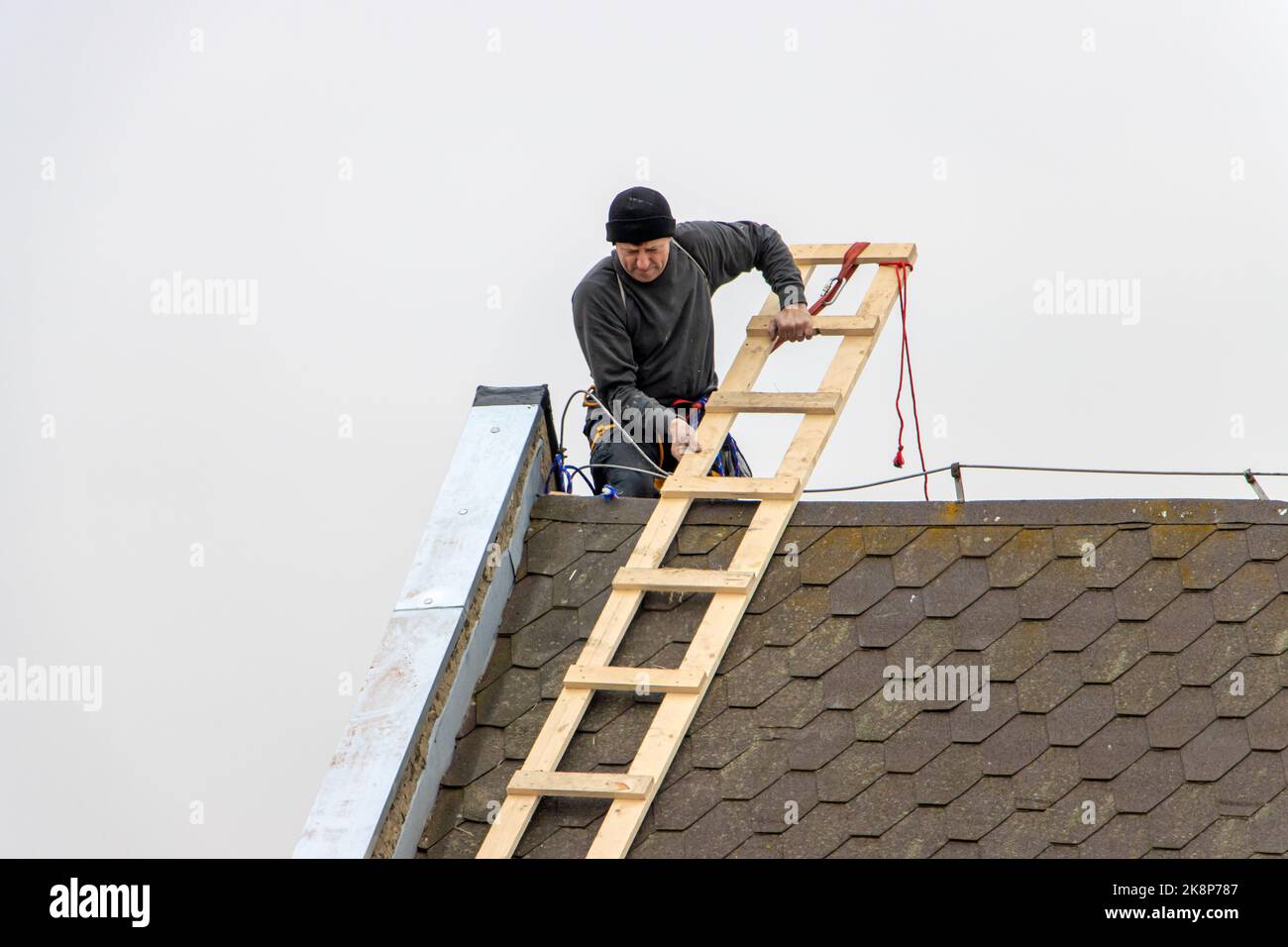 A repairman manipulates a ladder while repairing a roof Stock Photo - Alamy