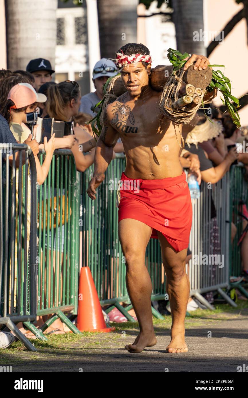 A vertical shot of a man with an athletic physique running with a log ...
