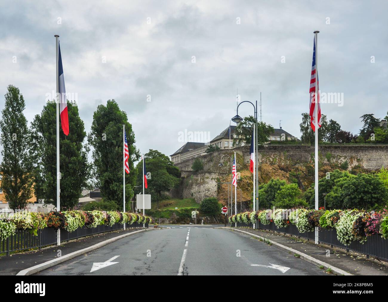 A road surrounded by hanging flags from poles and blooming flowers in ...