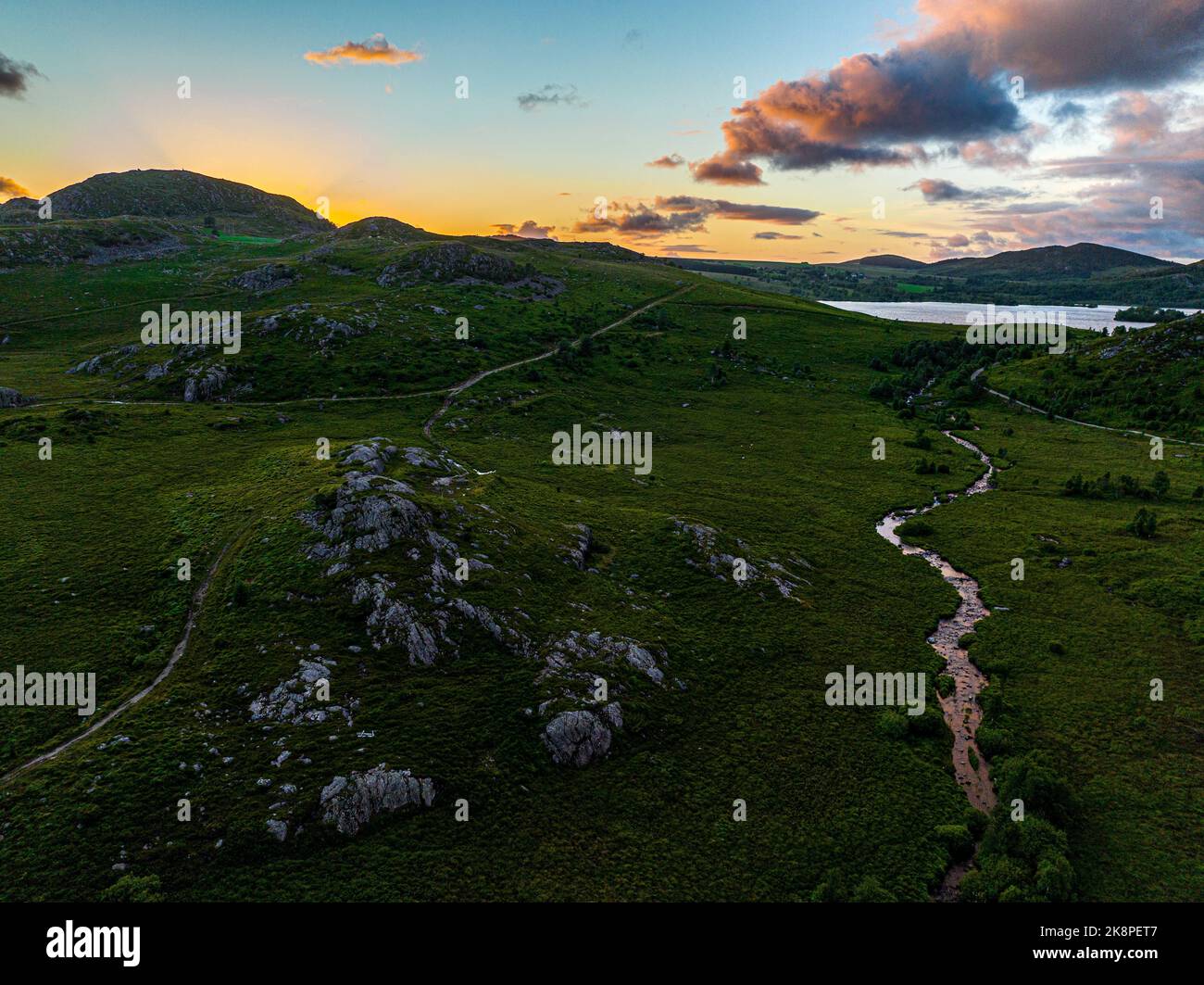 A beautiful sunset over a landscape displaying a narrow river and green ...