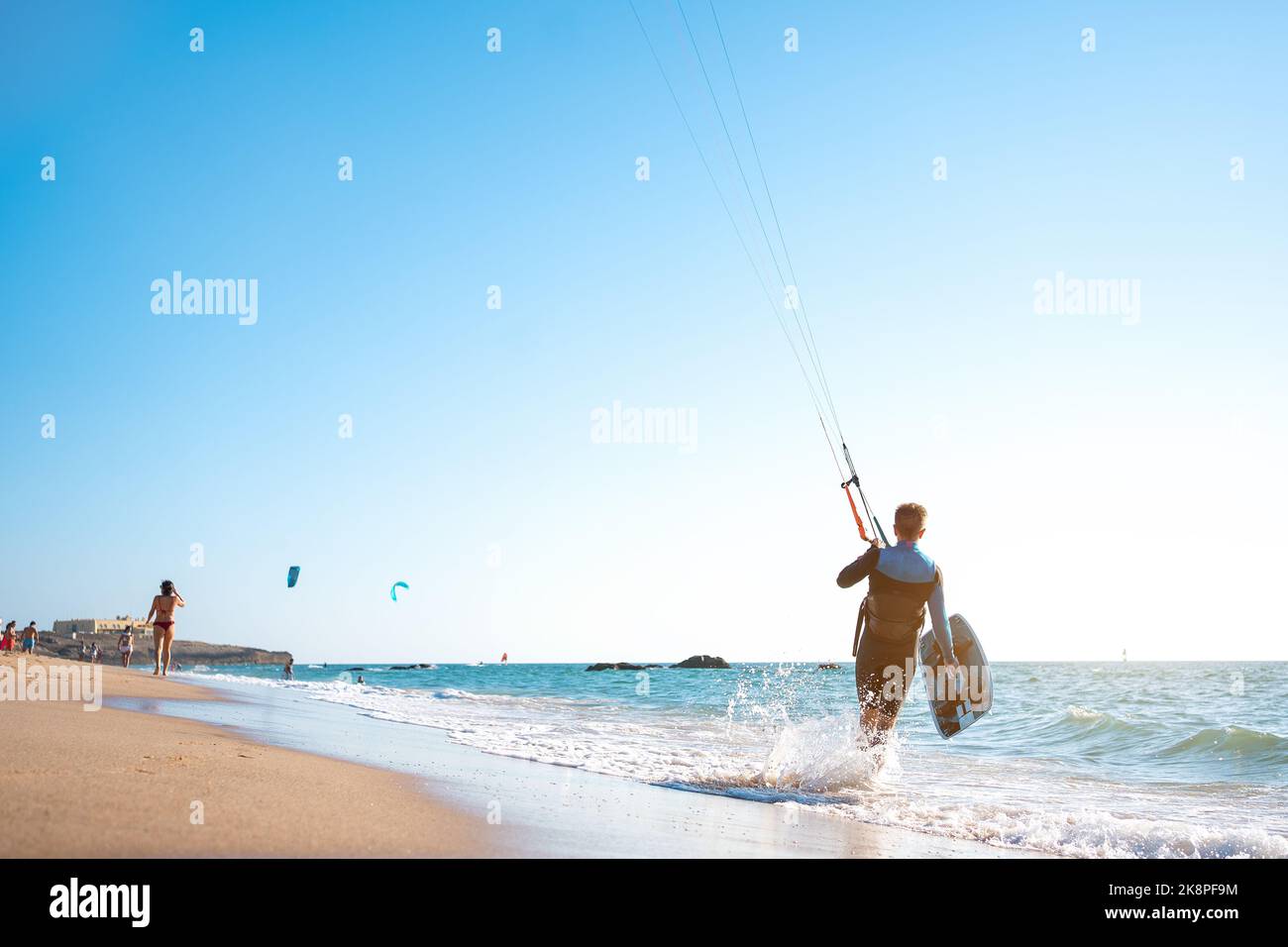 Portrait wave kitesurfer walking upwind at beach with his board and ...