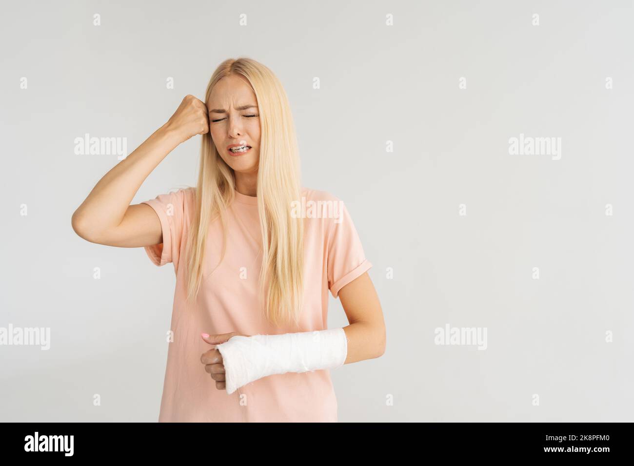 Studio portrait of suffering young woman with broken arm wrapped in ...