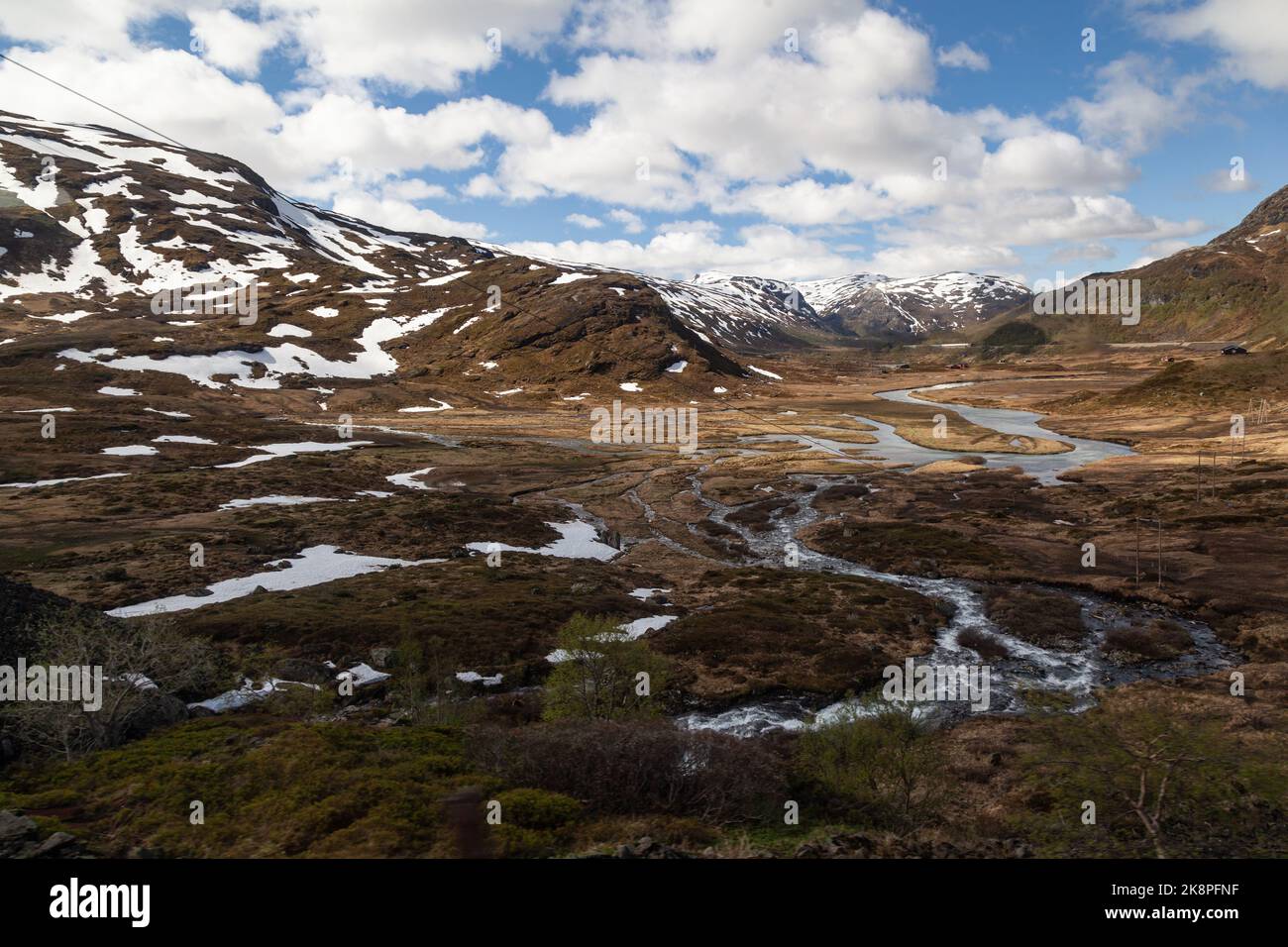 An aerial view of rural fields with flowing streams near snowy ...