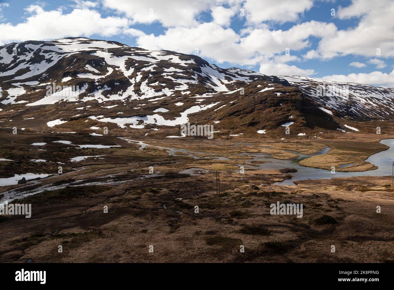 An aerial view of rural fields with flowing streams near snowy ...