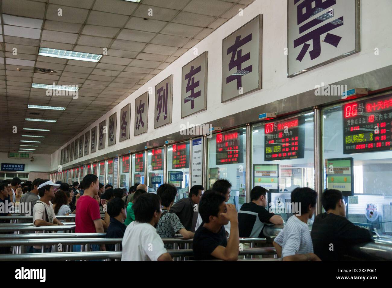 Commuters and travellers queue up at a line of ticket office windows to ...