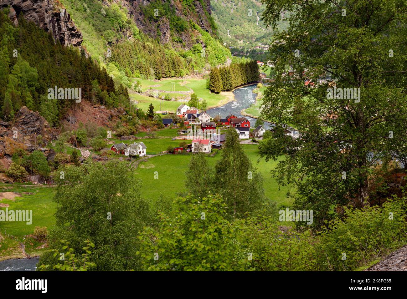 A small village in sunlight next to the river surrounded by forests and ...