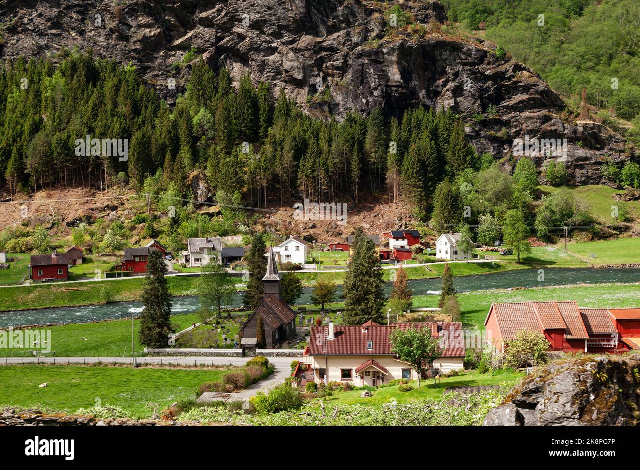 A small village in sunlight next to the river surrounded by forests and ...