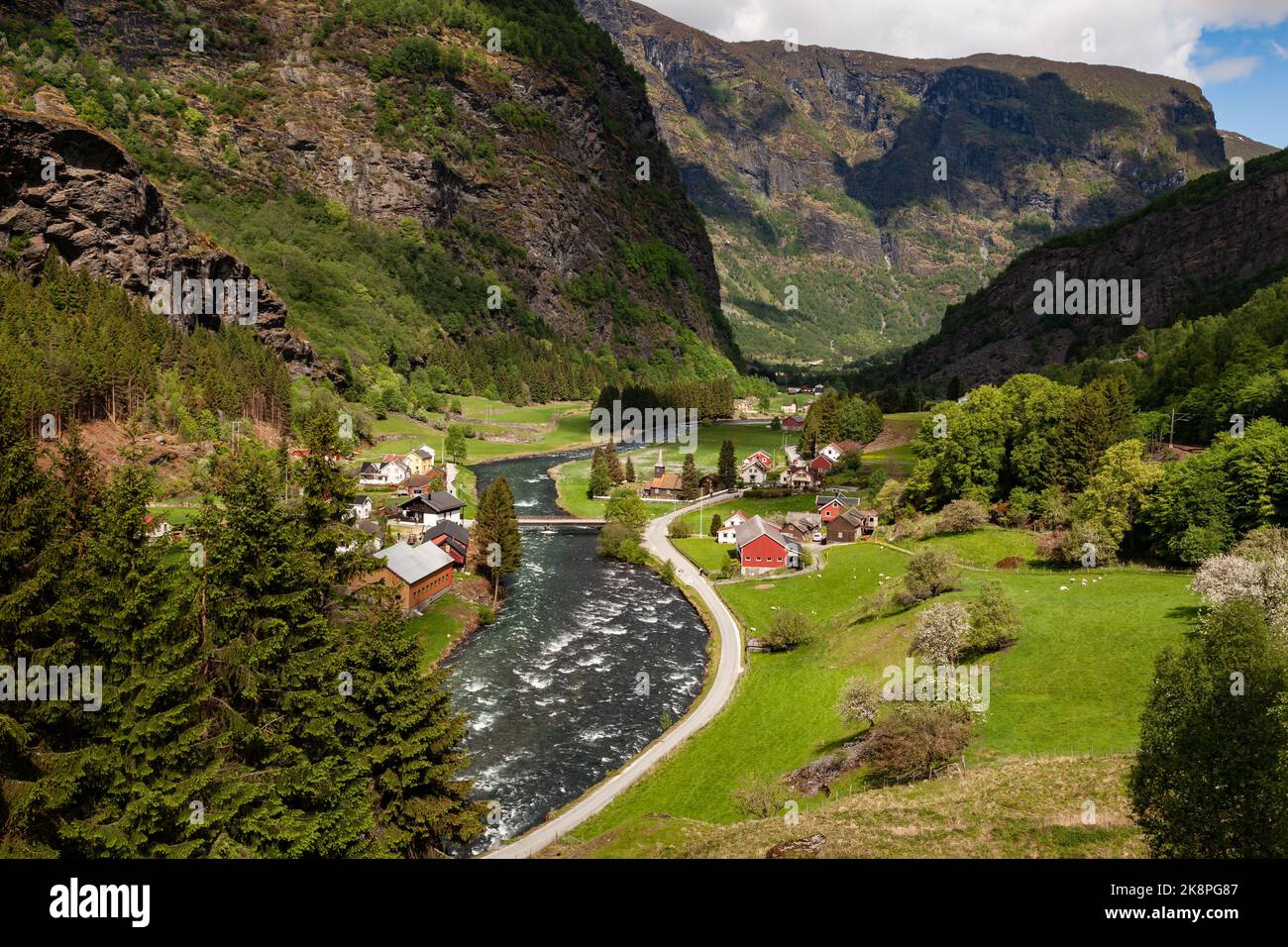 A small village in sunlight next to the river surrounded by forests and ...
