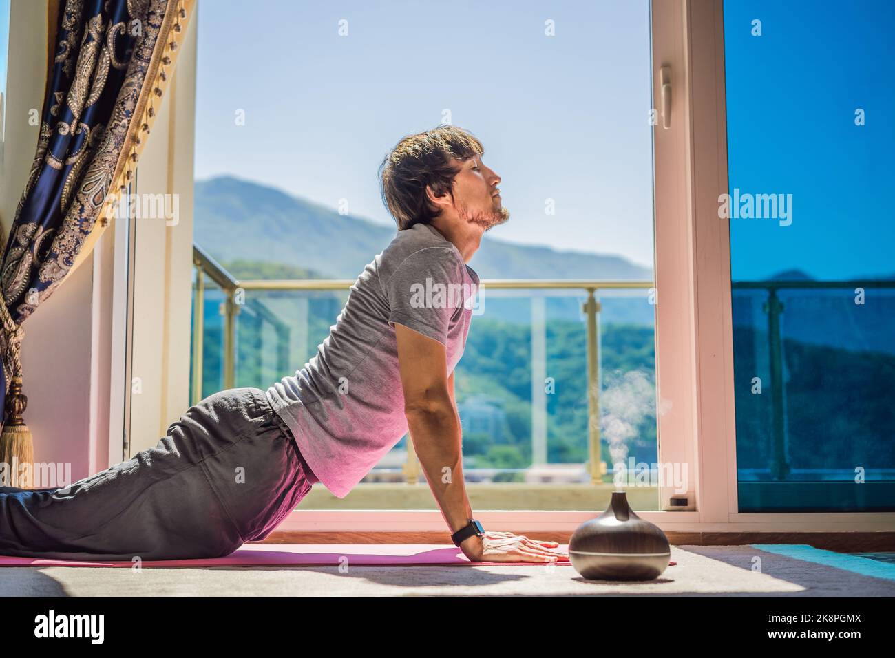 Mindful healthy man practicing yoga at home. Sitting on the floor doing ...