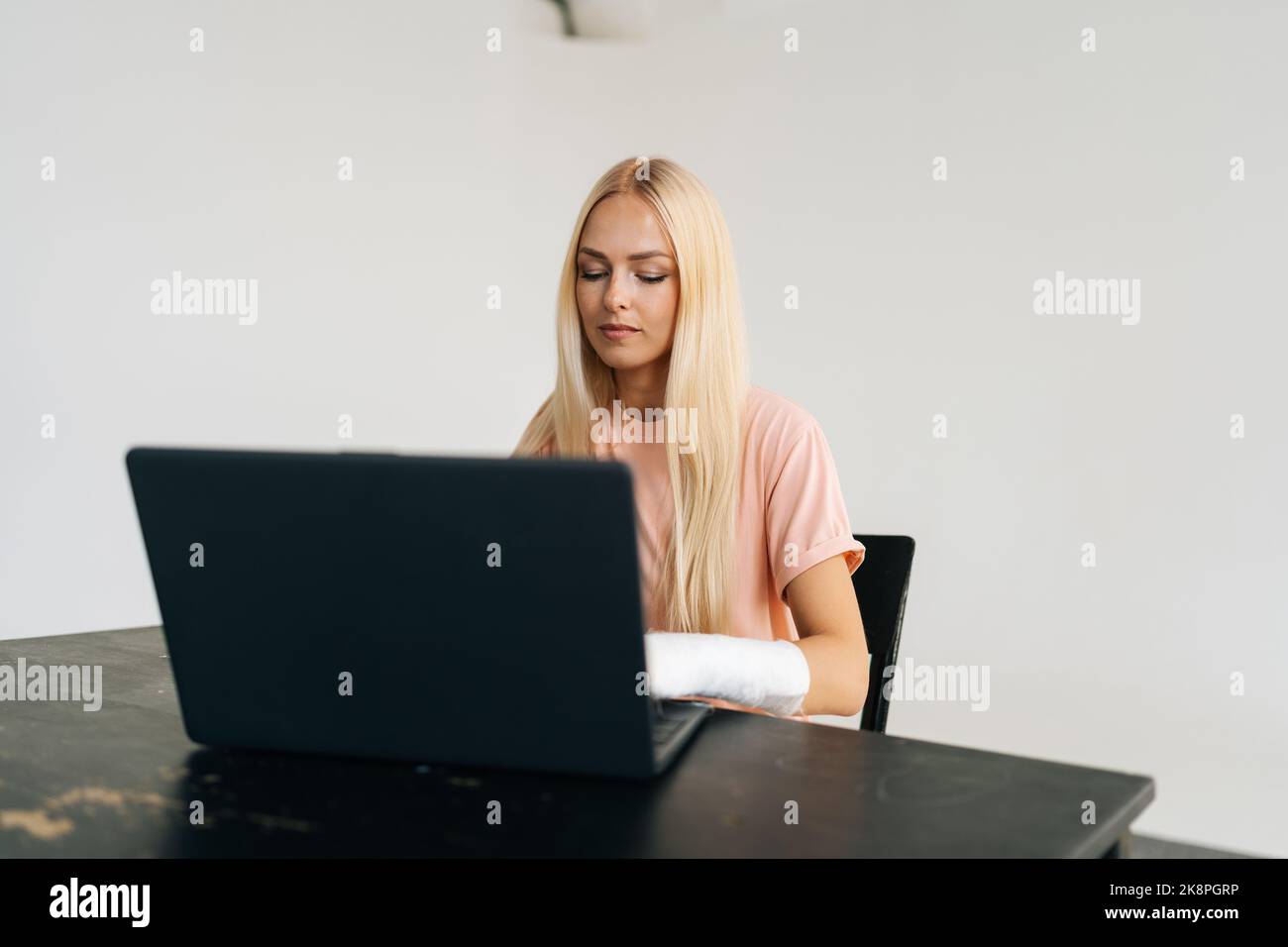 Studio portrait of focused injured young woman with broken arm wrapped ...