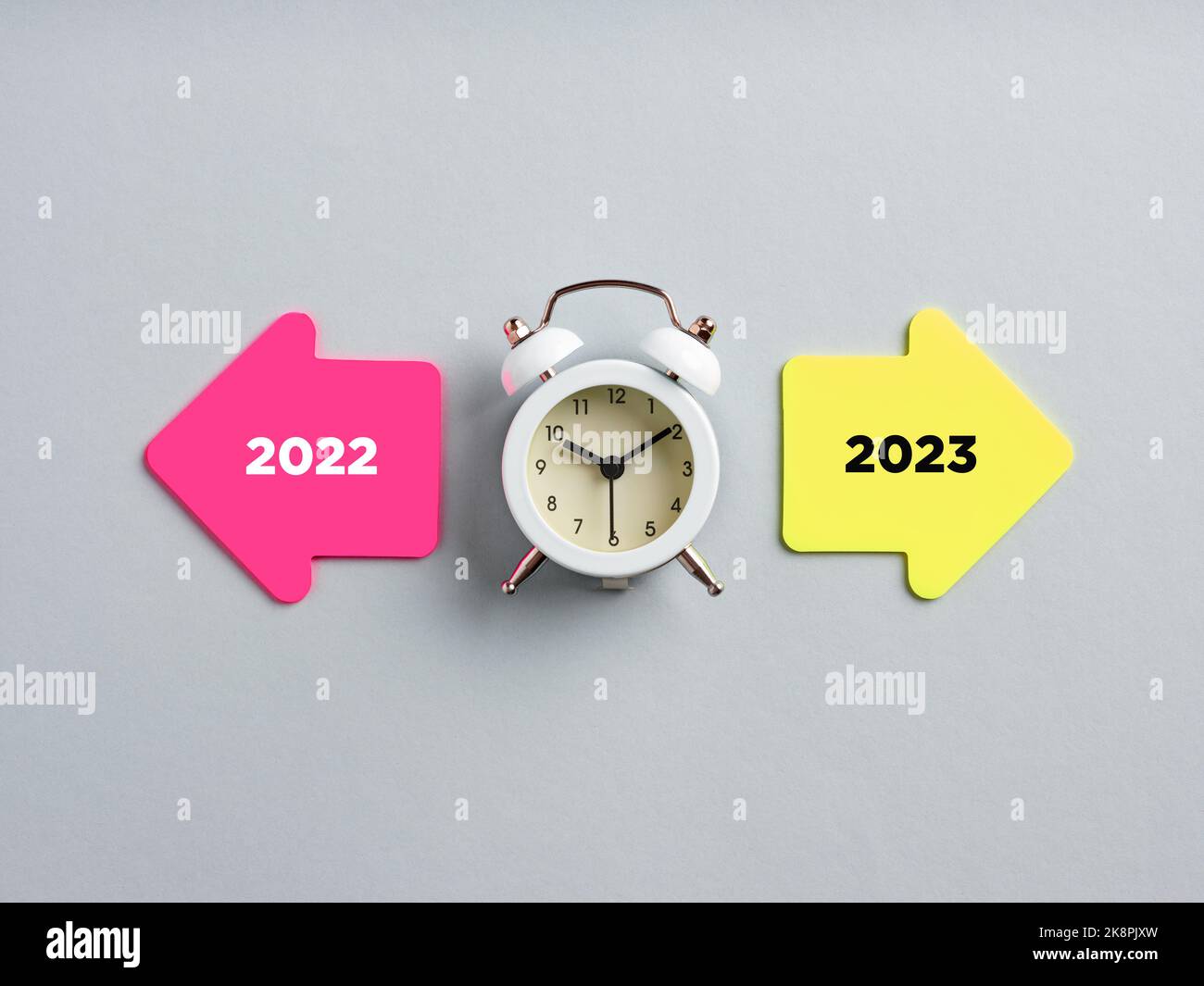 The year 2022 and 2023 written on arrow note papers next to a clock ...