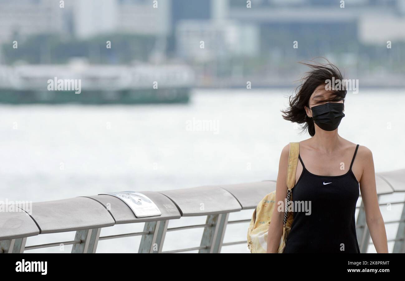 A woman walks along the waterfront of Victoria Harbour in Tsim Sha Tsui ...
