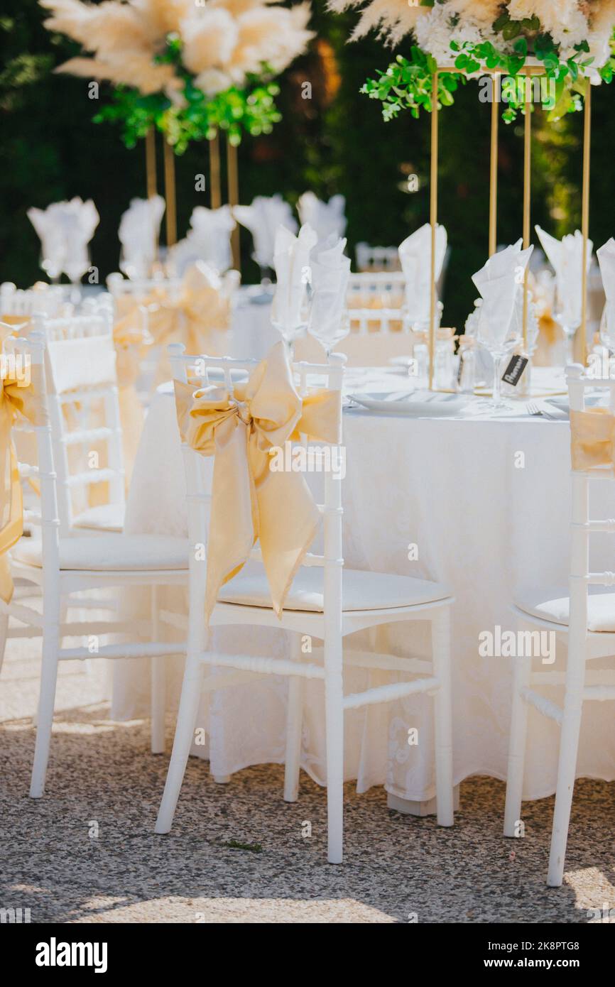 The ribbon bows on white chairs around white tables at outdoor wedding reception venue Stock ...