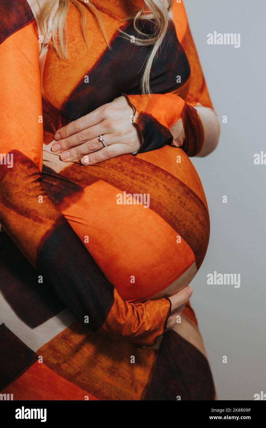A portrait of a pregnant female hugging her baby bump - maternity shoot ...