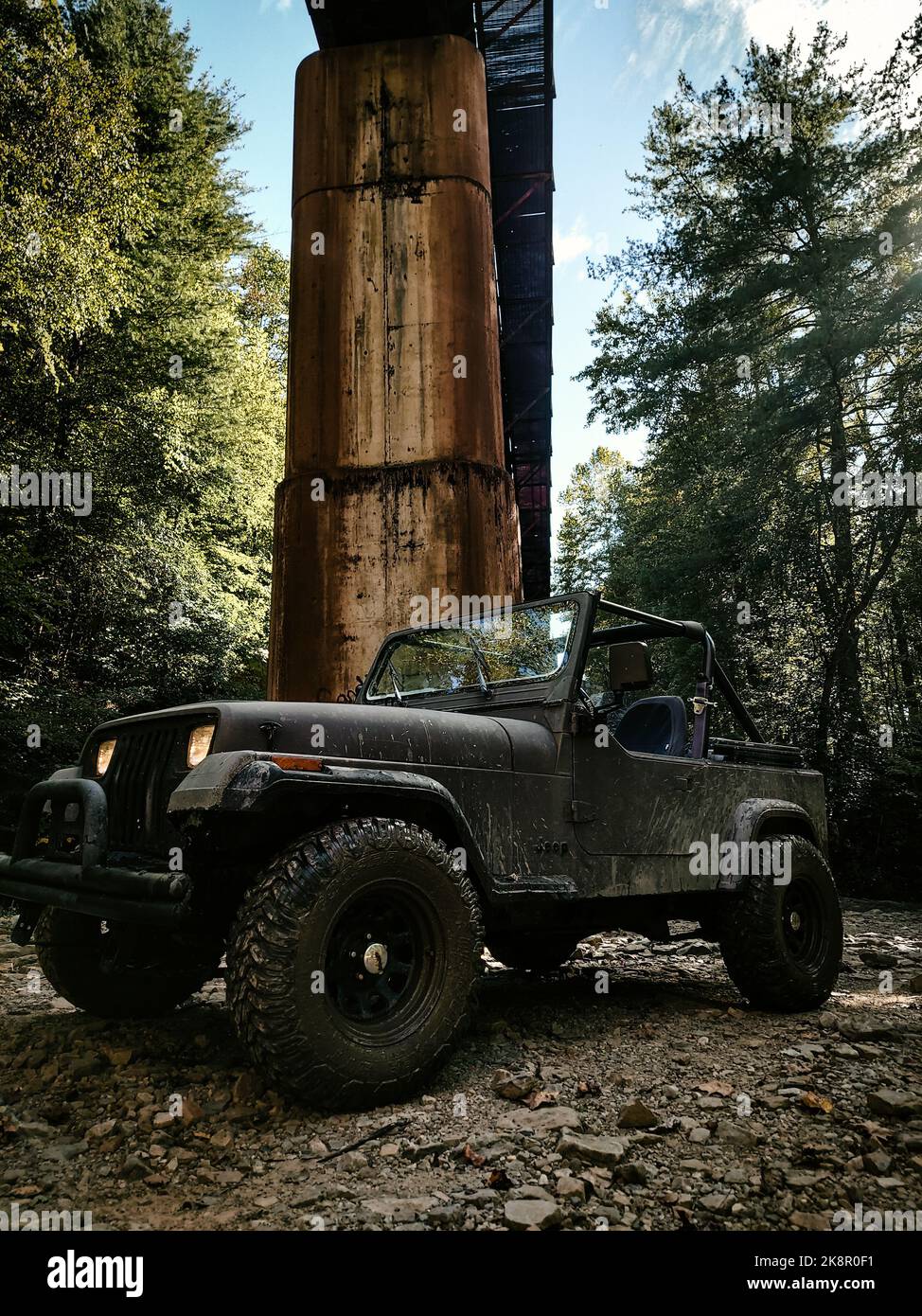 A vertical shot of dark green Jeep Wrangler by wooden construction in ...