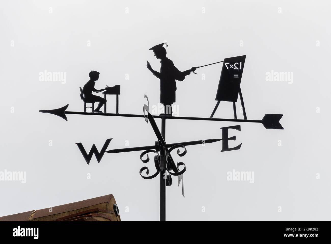 Weather vane on an old school, with teacher wearing mortice board and ...