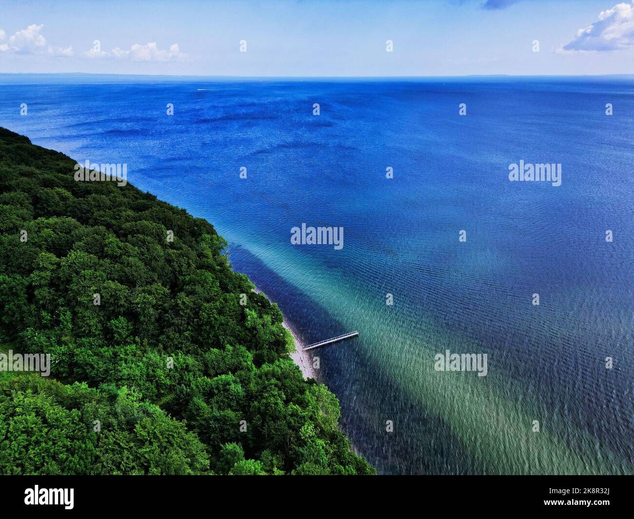 An aerial view of the green coastline and seascape under the blue sky ...