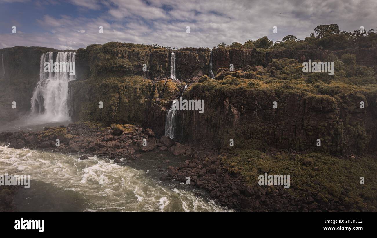 A scenic shot of two waterfalls on a hill flowing into a lake on a ...