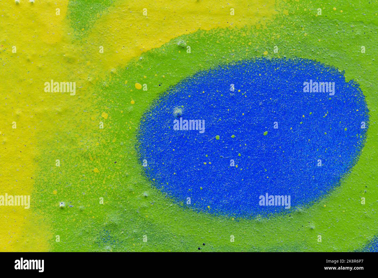 Macro close-up of a wall spray painted with yellow, light green and ...