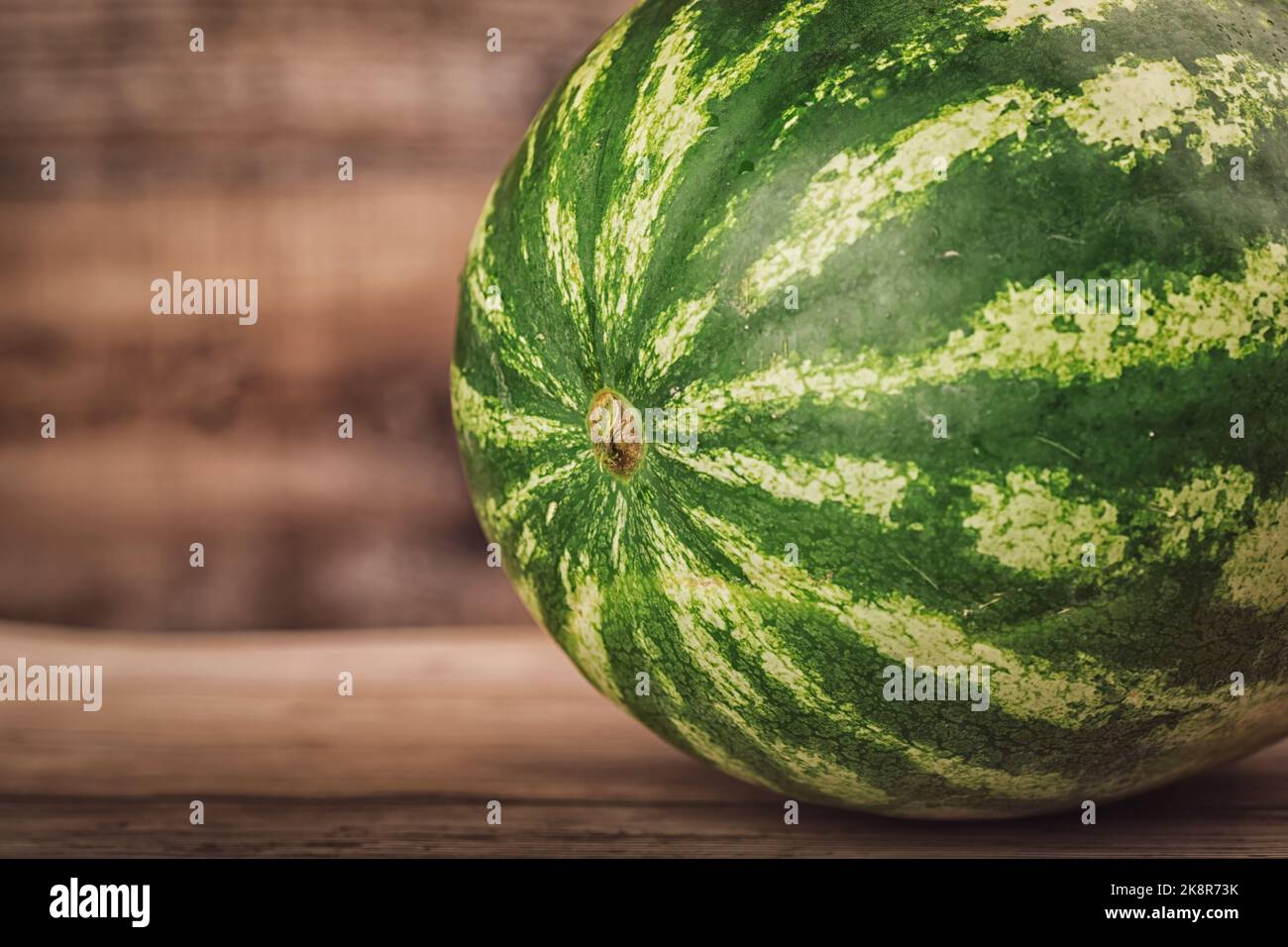 A closeup of whole round watermelon on blur wooden background Stock ...