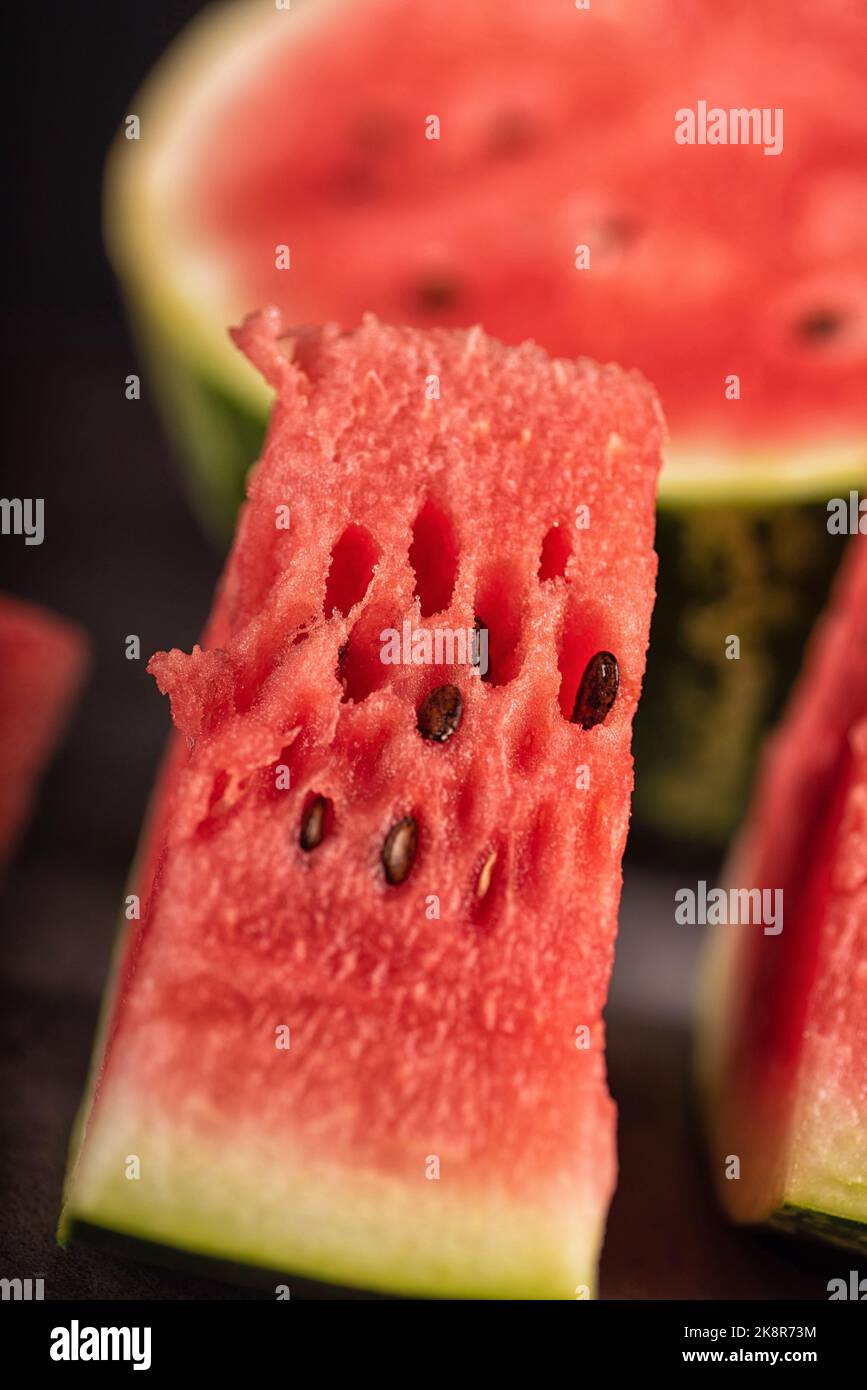 A vertical closeup of watermelon slice and blur halved watermelon Stock ...