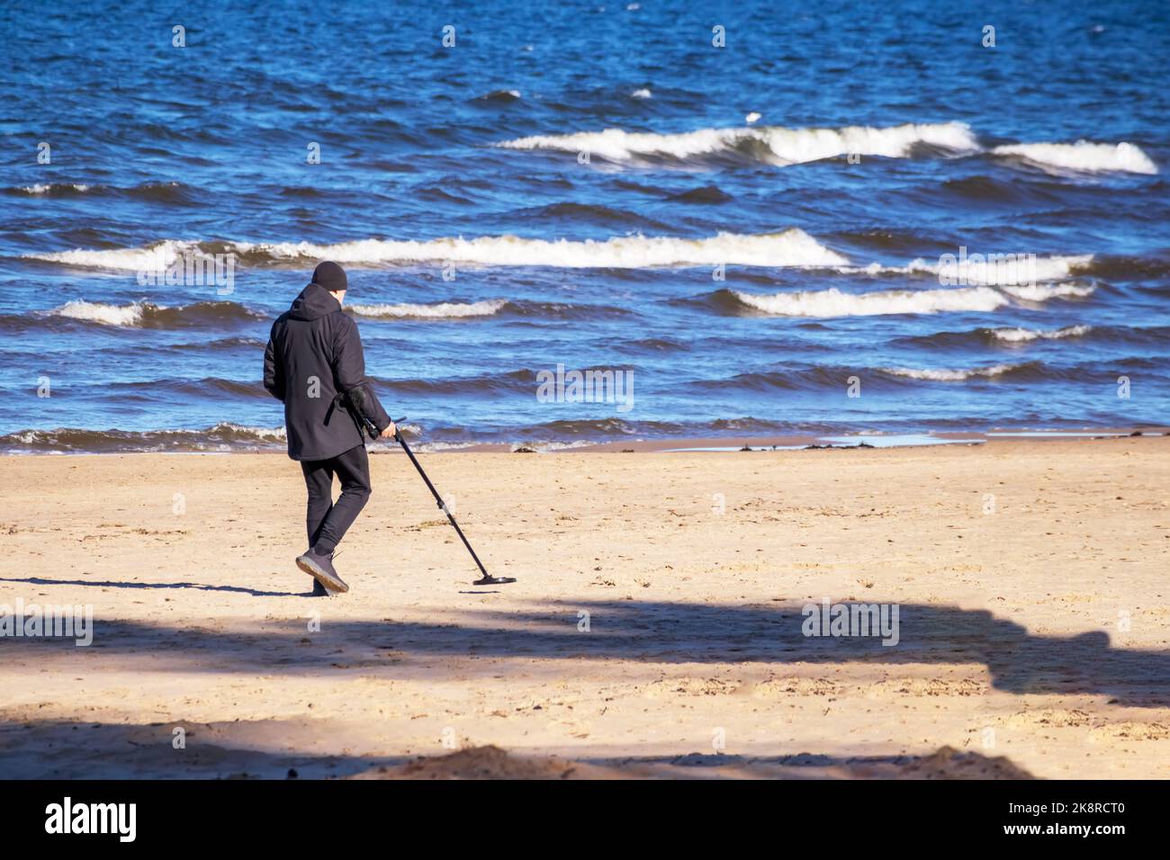 Person with a metal detector walking by the beach finding treasures ...