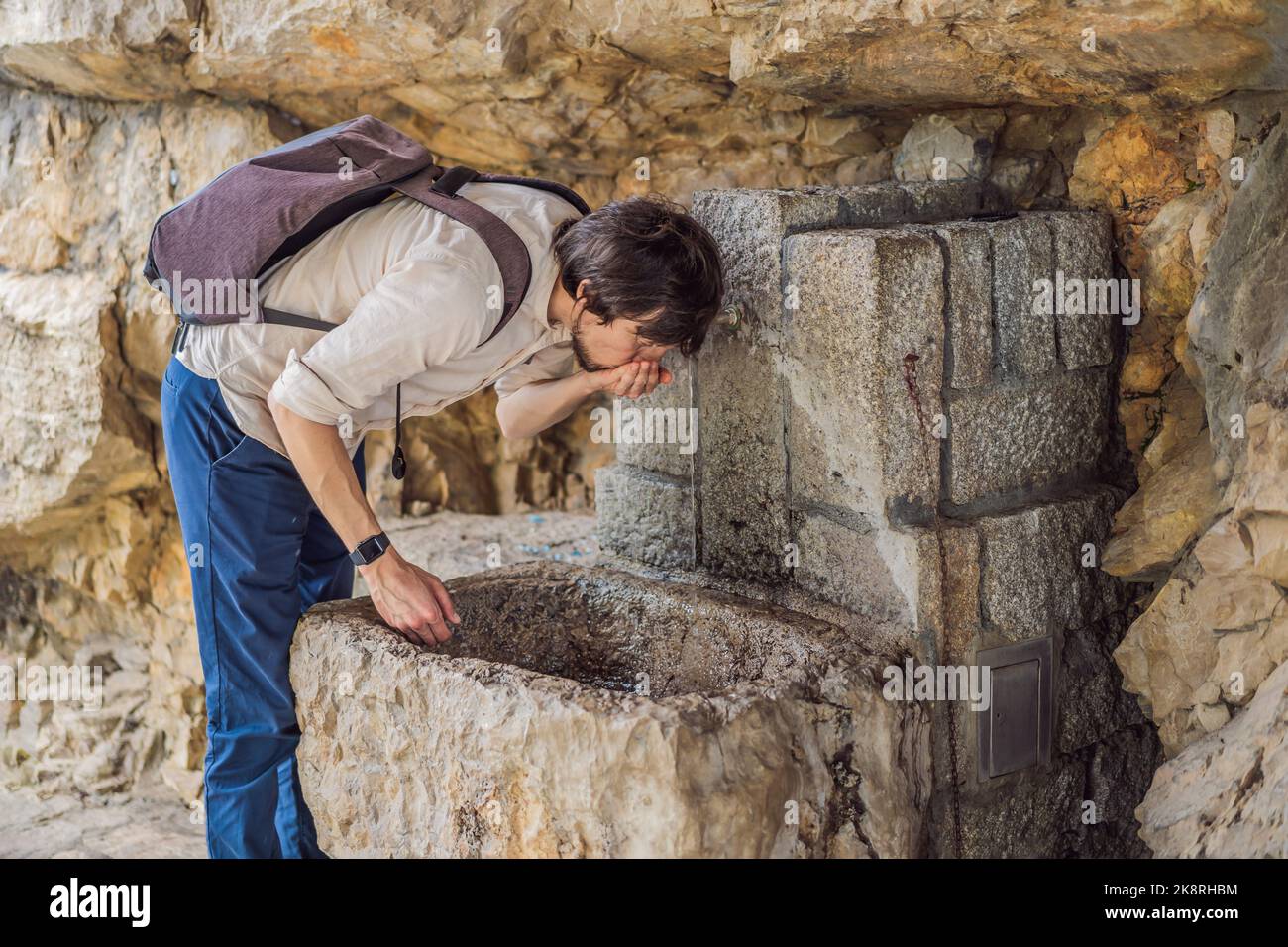 Man tourist in Monastery of Ostrog, Serbian Orthodox Church situated against a vertical ...