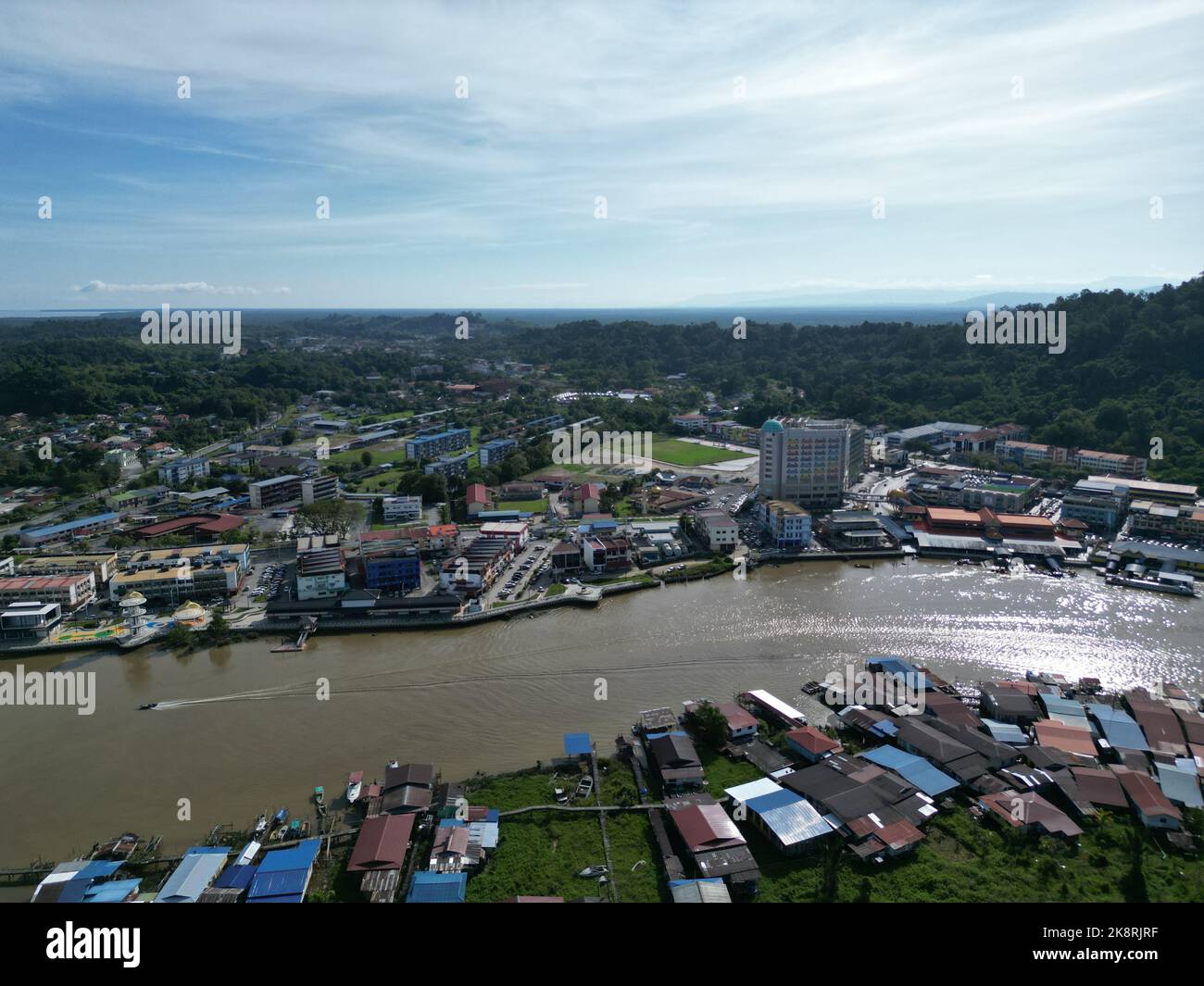 An aerial view of a city built next to a riverbed with a beautiful landscape in the background ...