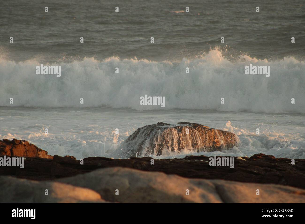 A scenic view of strong sea waves hitting the rocks on the shoreline of ...