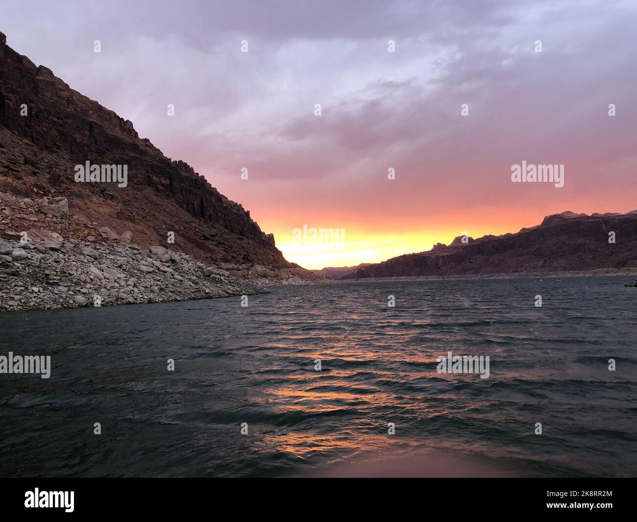 A view of the seascape before the mountains under the cloudy orange ...