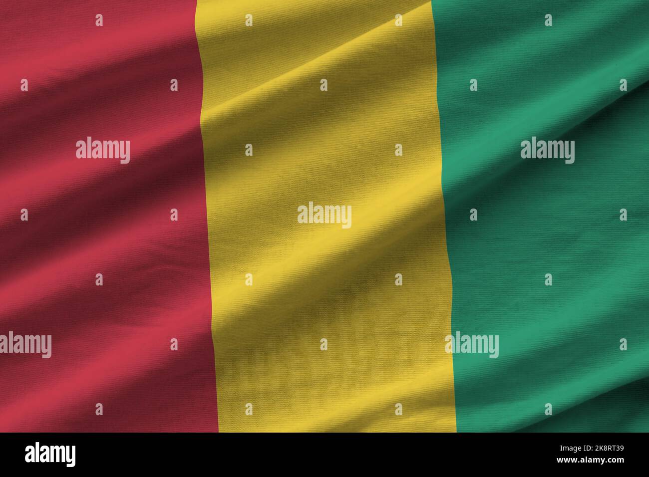 Guinea flag with big folds waving close up under the studio light ...