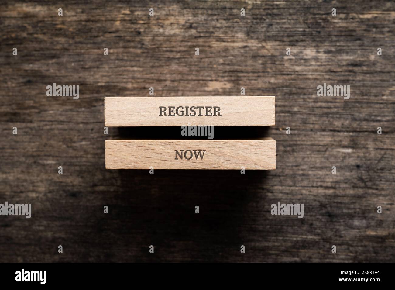 Register now sign written on two wooden pegs placed over rustic wooden ...