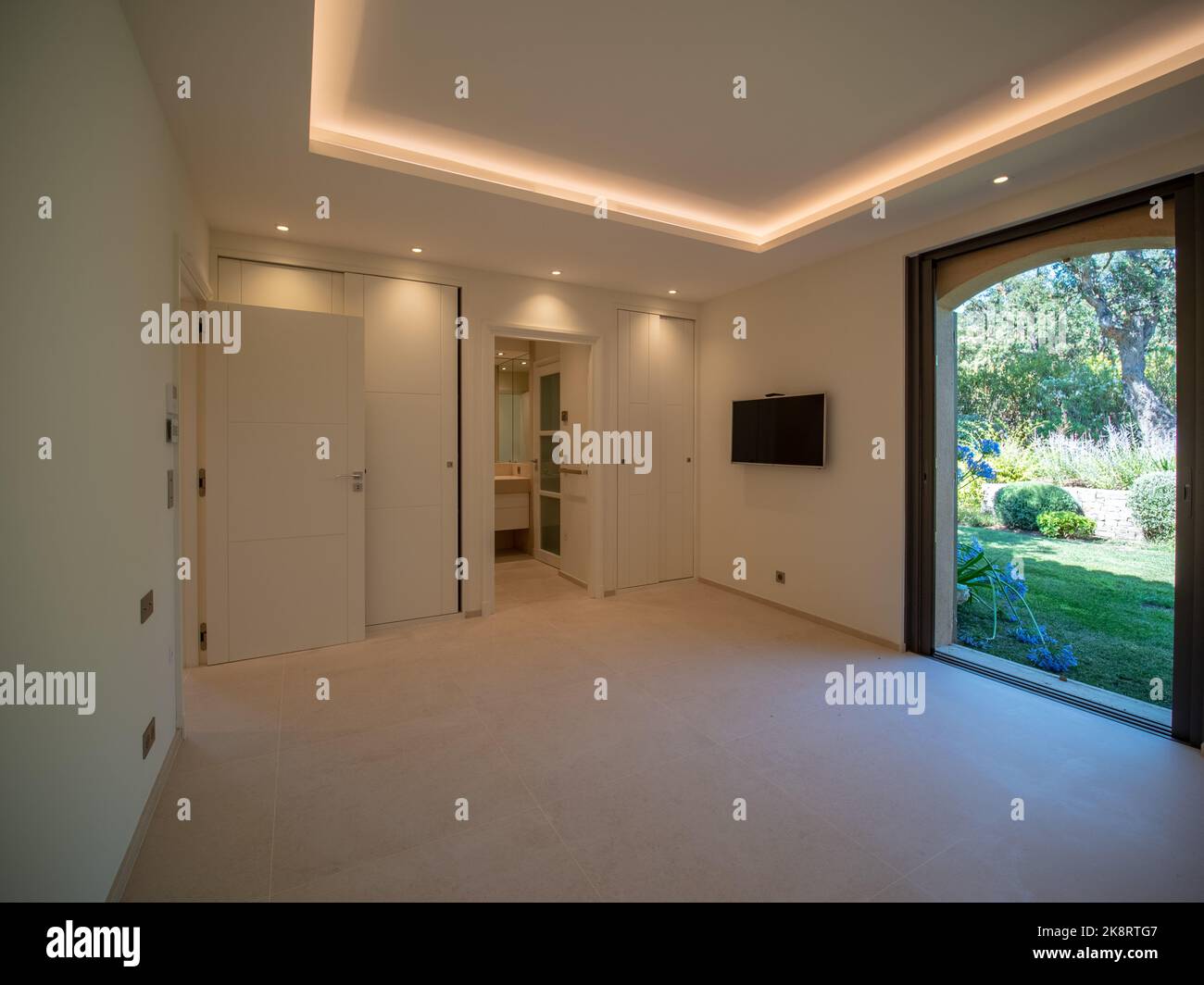 A modern spacious room with an open door on the left, cupboards, and a ...