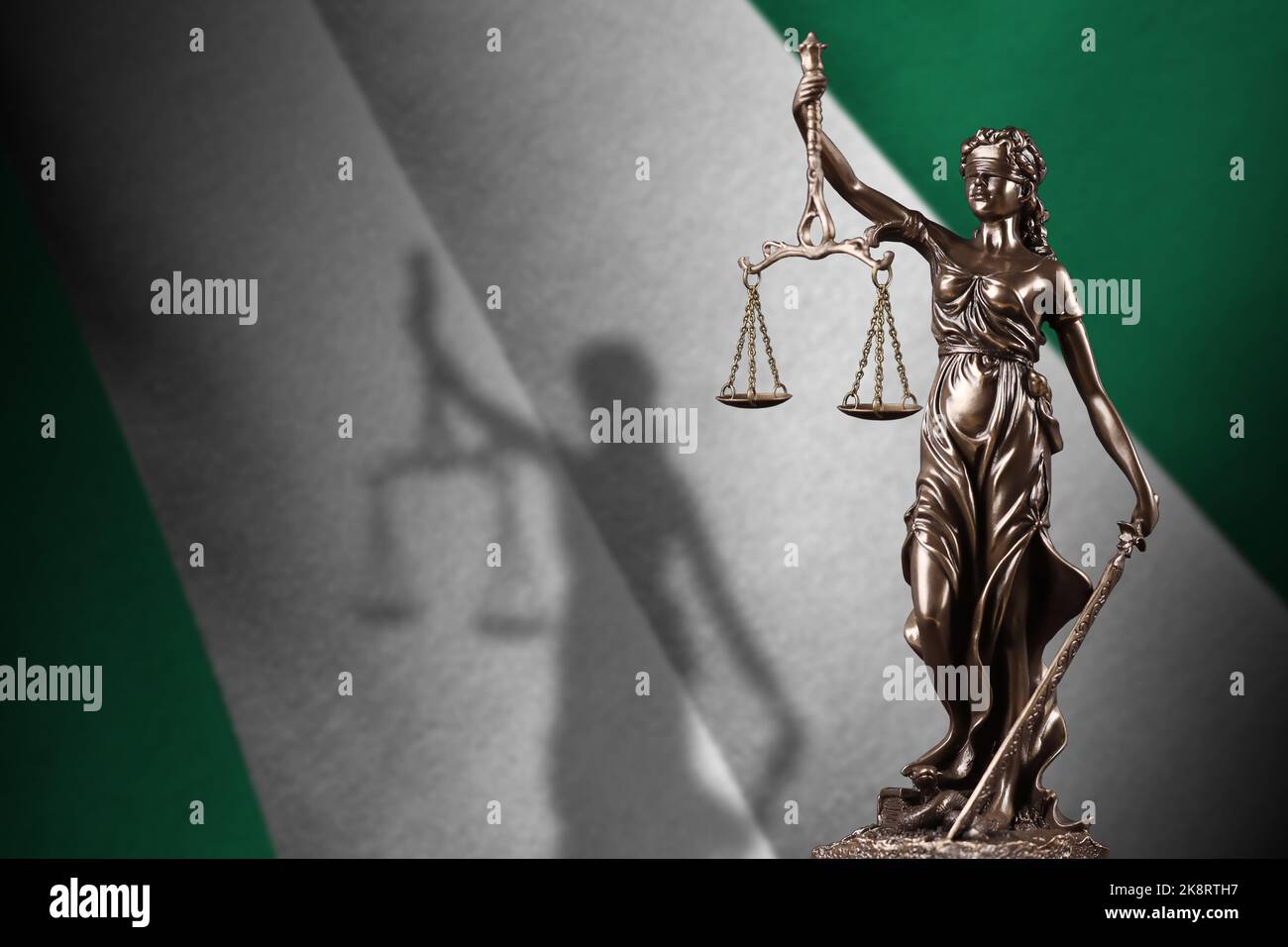 Nigeria flag with statue of lady justice and judicial scales in dark ...