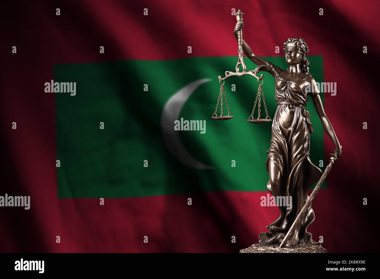 Maldives flag with statue of lady justice and judicial scales in dark ...